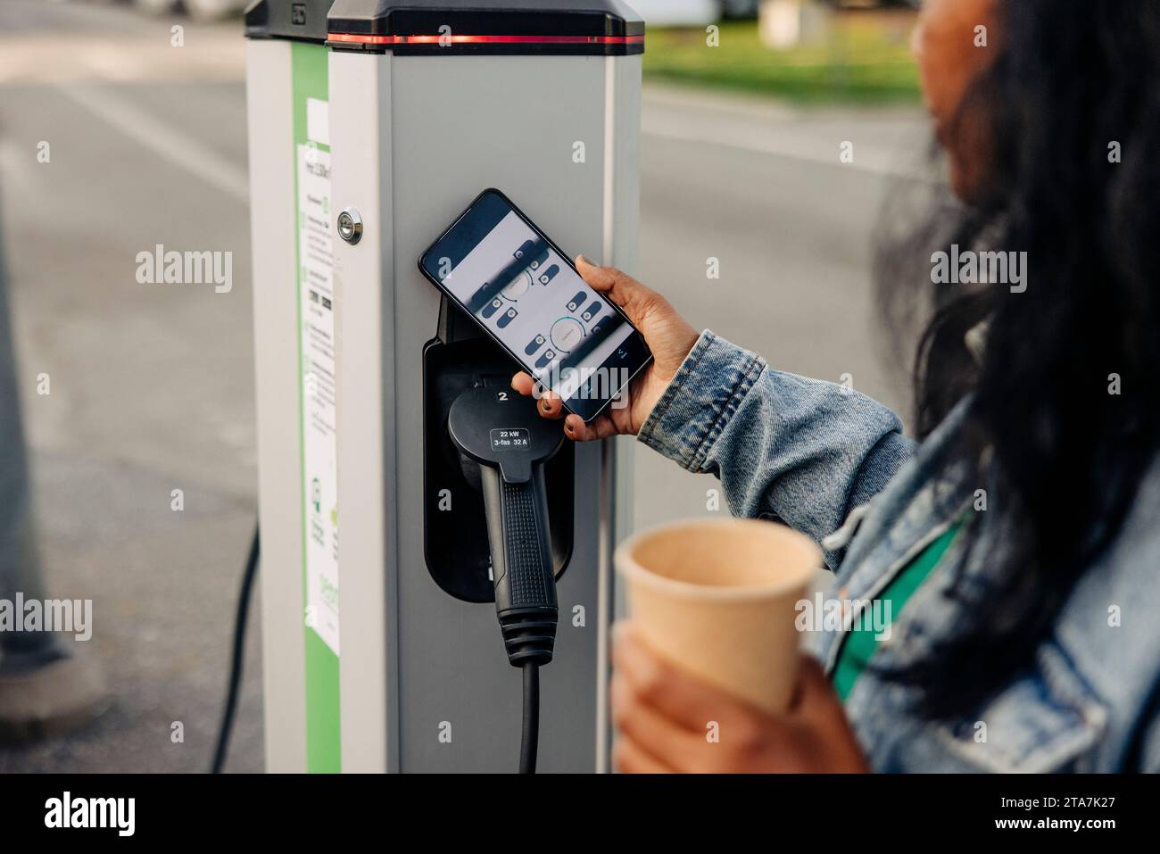 Woman using app on smart phone near kiosk at charging station Stock ...