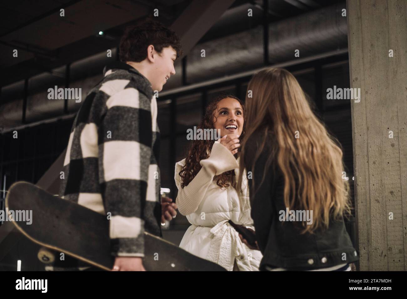 Low angle view of excited girl talking with male and female teenage ...