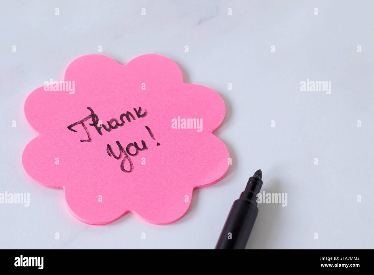 Thank You handwritten text on pink sticky note in flower shape with ...