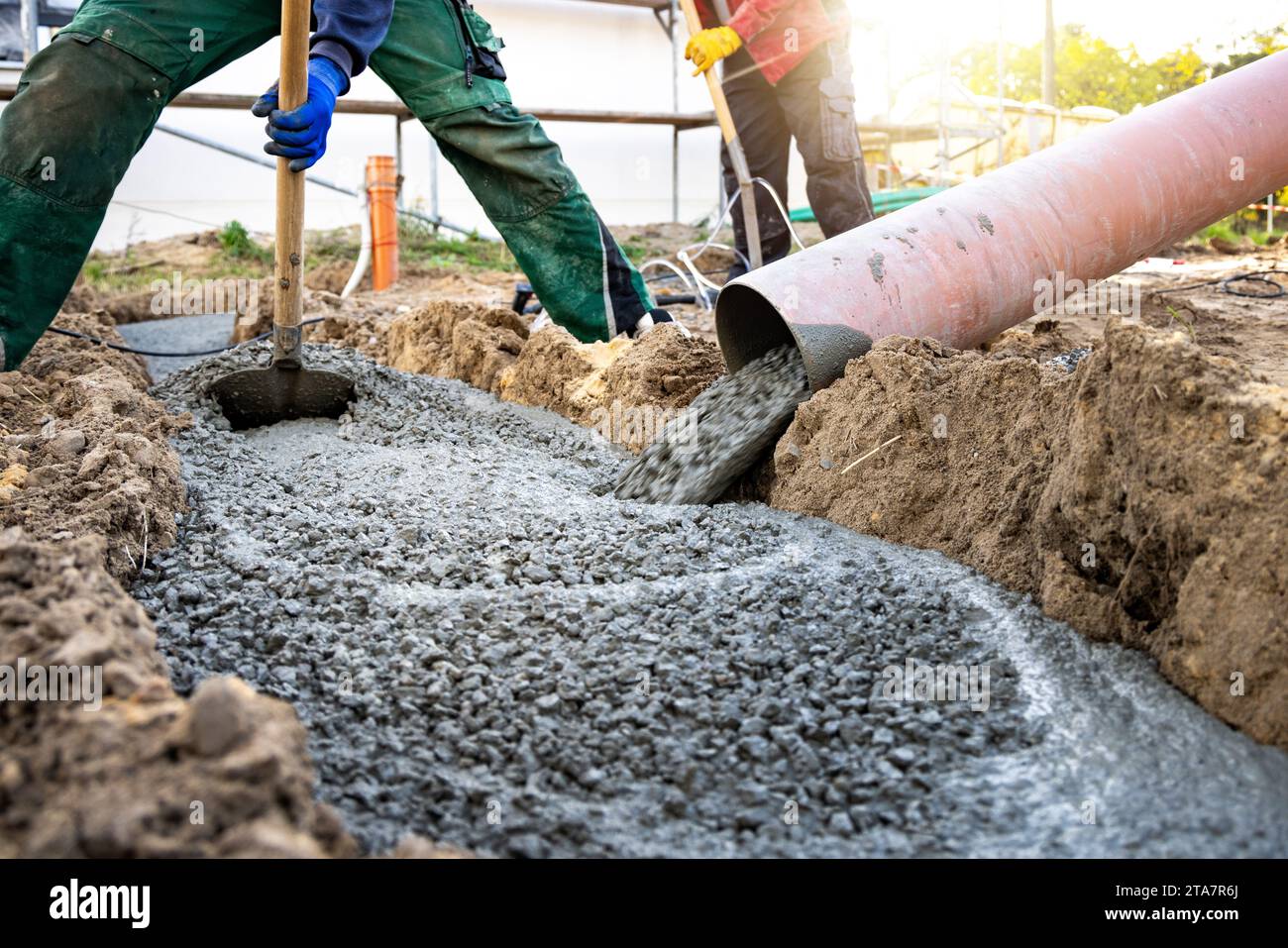 Construction worker spreading fresh concrete for a building foundation ...