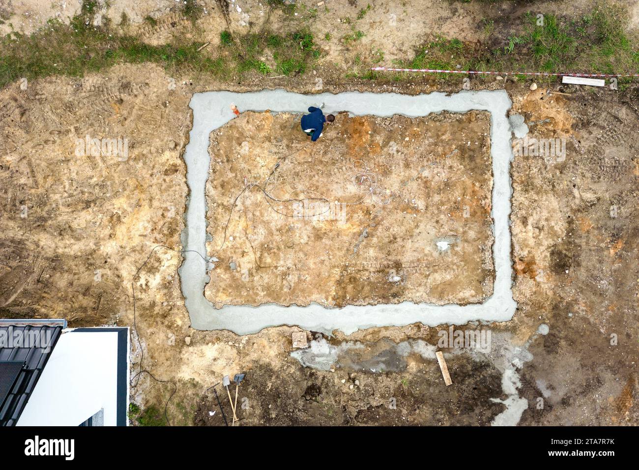 Aerial view of a freshly poured concrete foundation next to a single ...