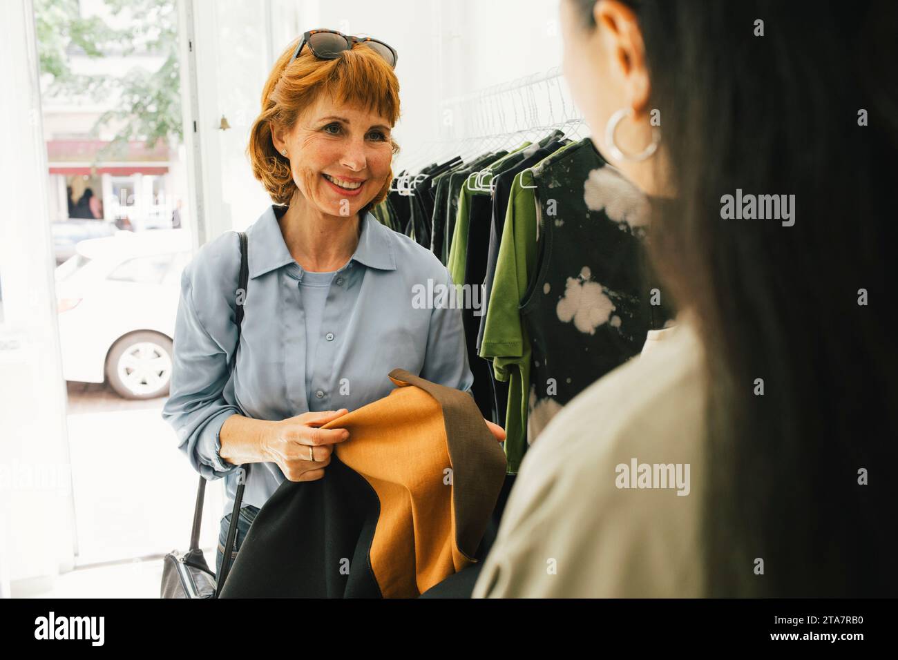 Smiling senior customer talking with female sales staff while shopping ...