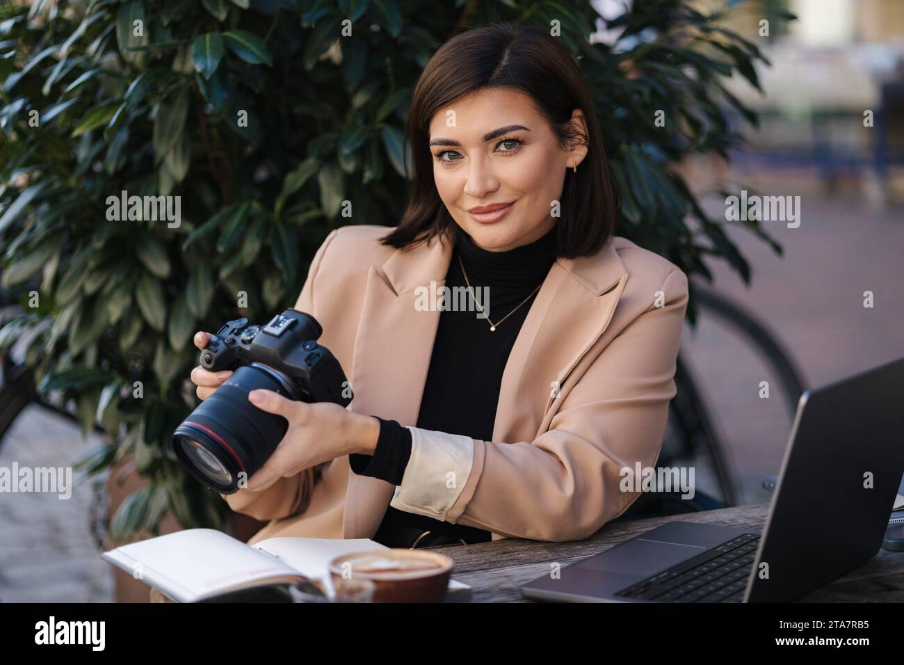 Portrait of attractive female photographer hold mirrorless camera in ...