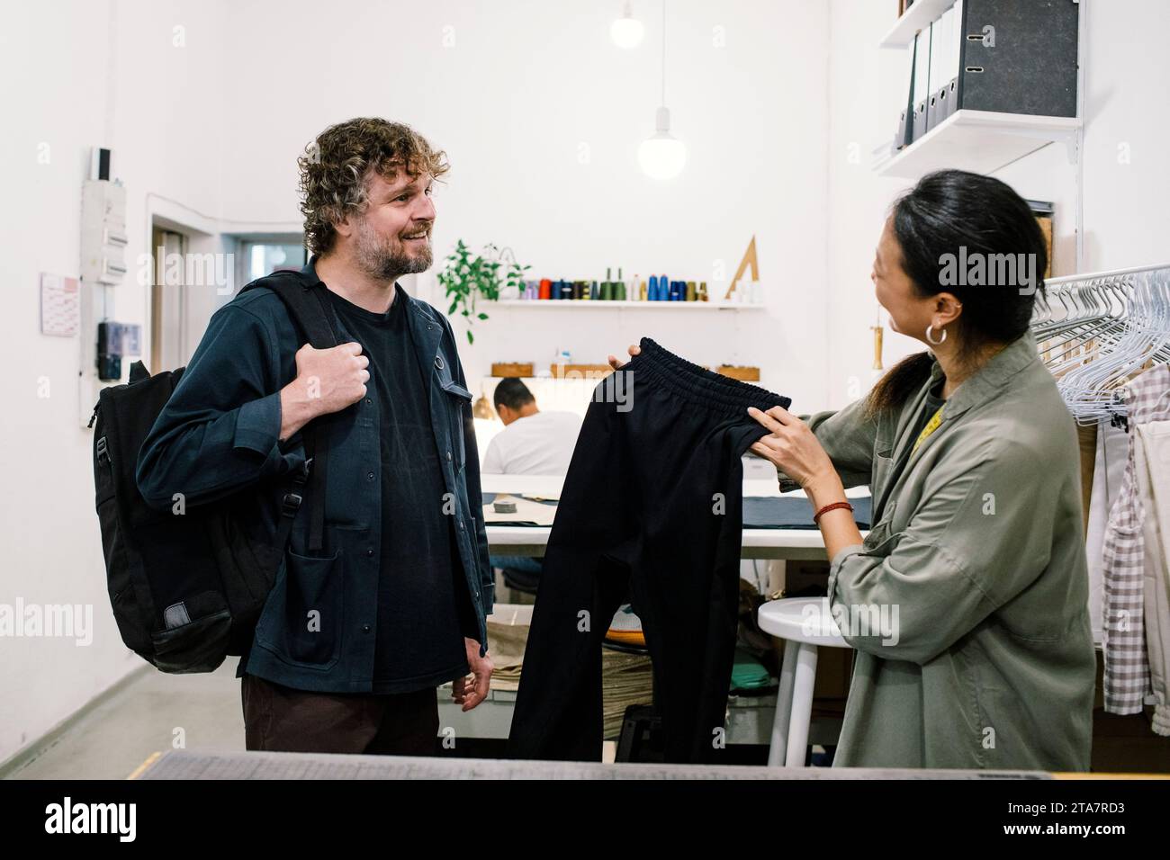 Female sales staff showing pants to male customer at workshop Stock ...