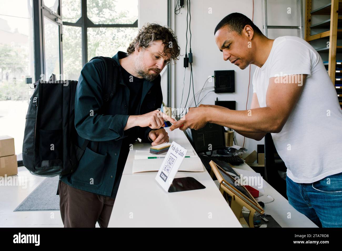 Mature male owner assisting customer while doing online payment at ...