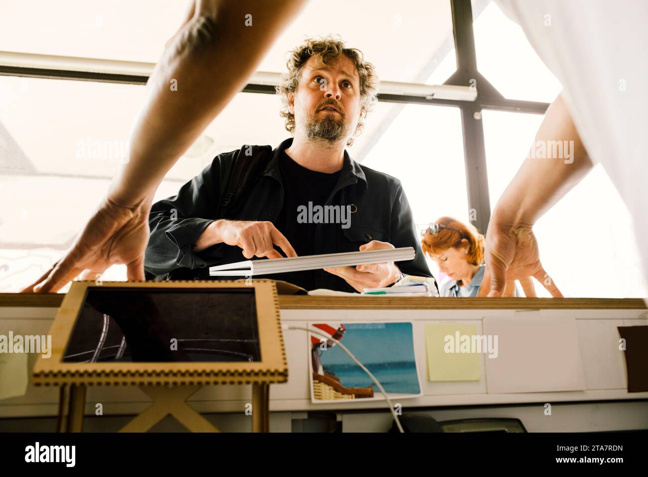 Low angle view of male customer holding damaged laptop while talking ...