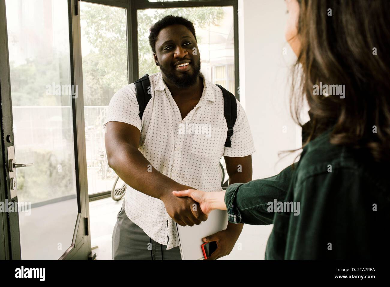 Smiling male customer doing handshake with technician at repair shop ...