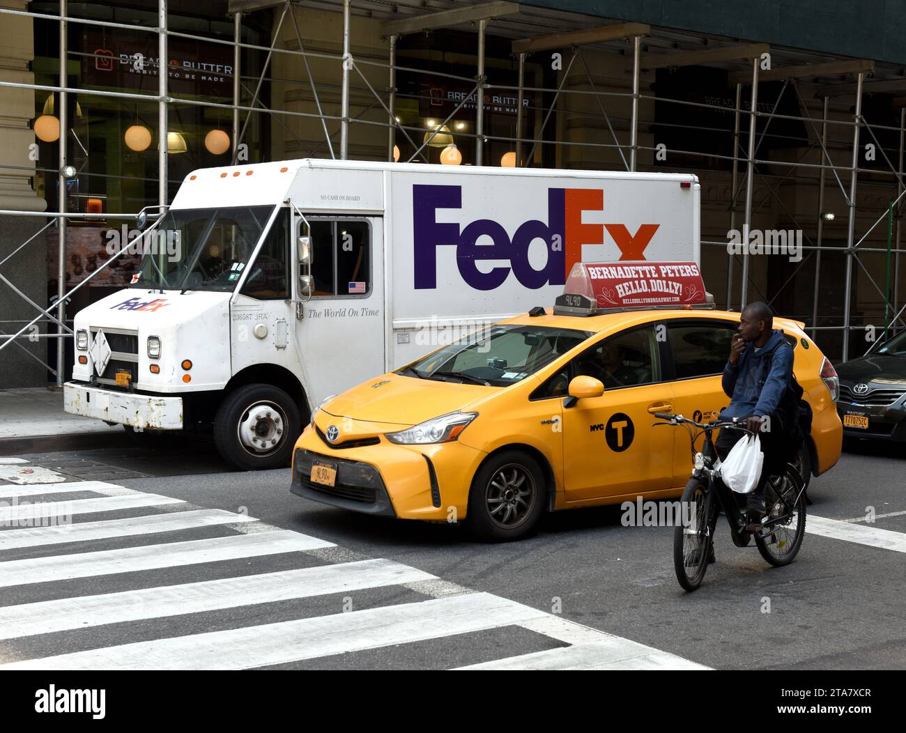 New York, USA - May 30, 2018: Man on a bike, taxi and car of FedEx on ...