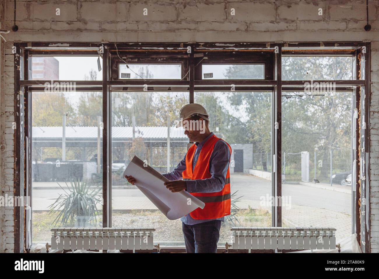The foreman at the construction site is carefully studying the project ...