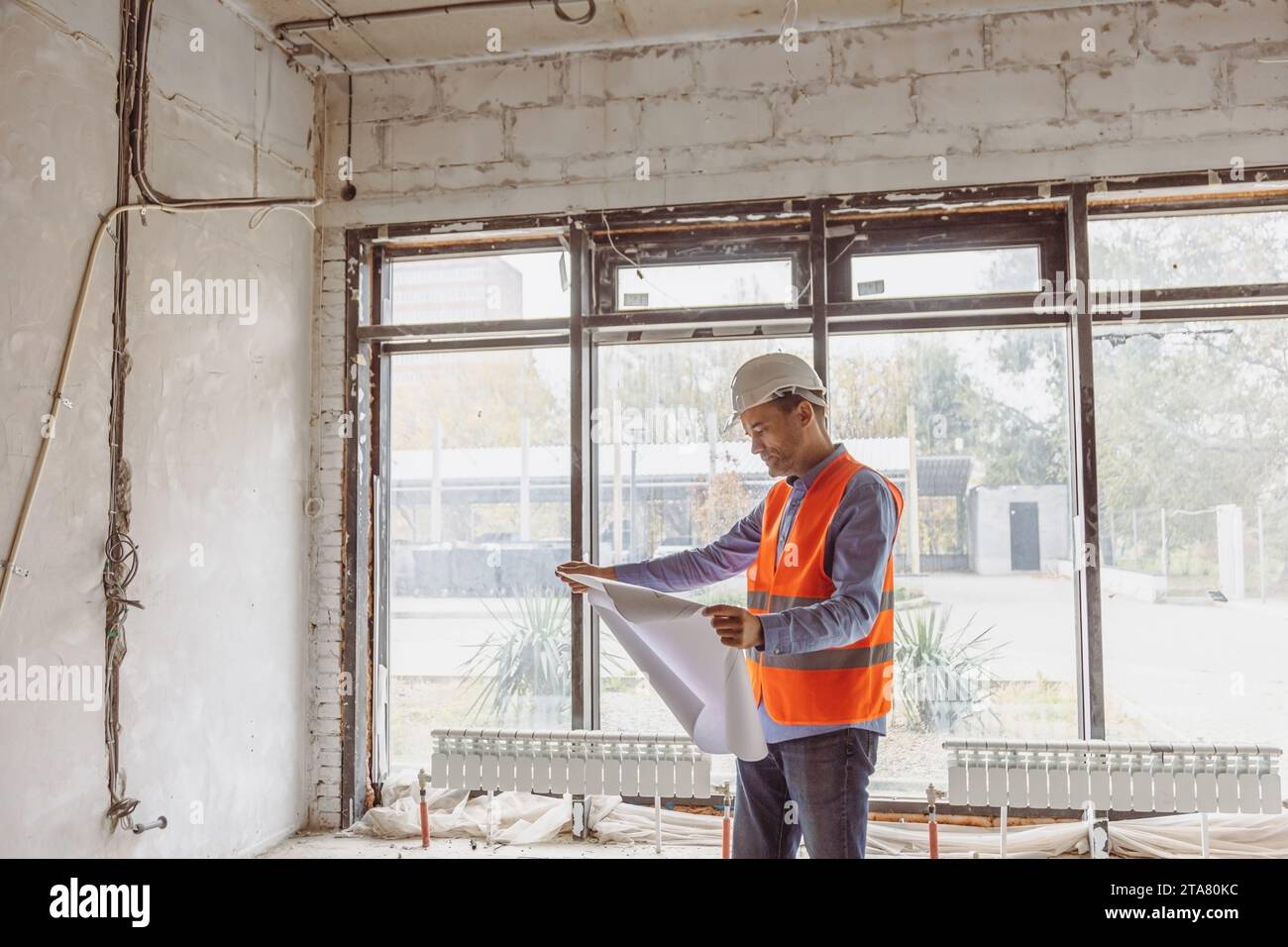 The foreman at the construction site is carefully studying the project ...