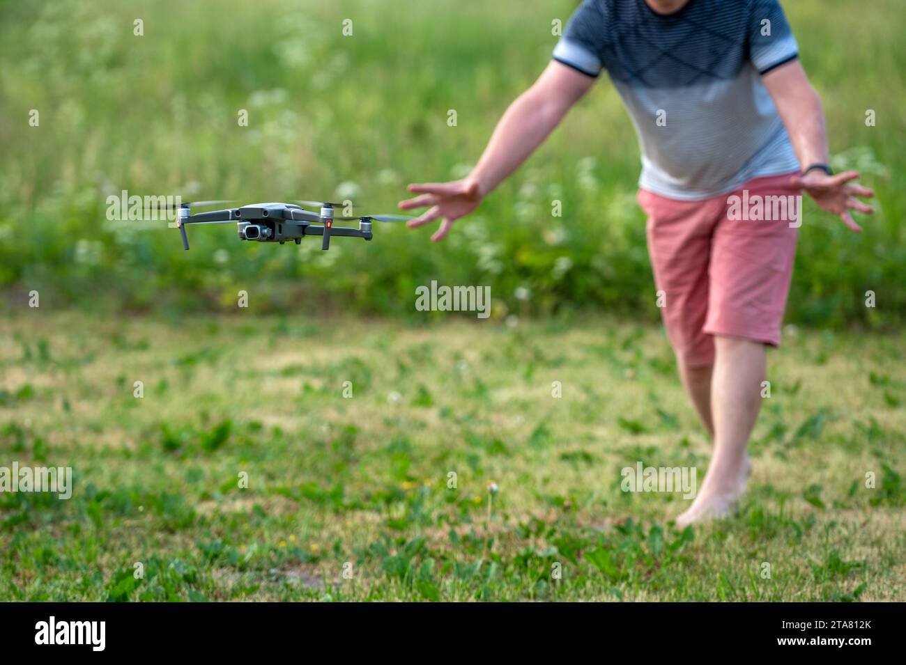 Drone quadcopter with digital camera flying over green grass. A man launches a drone Stock Photo ...