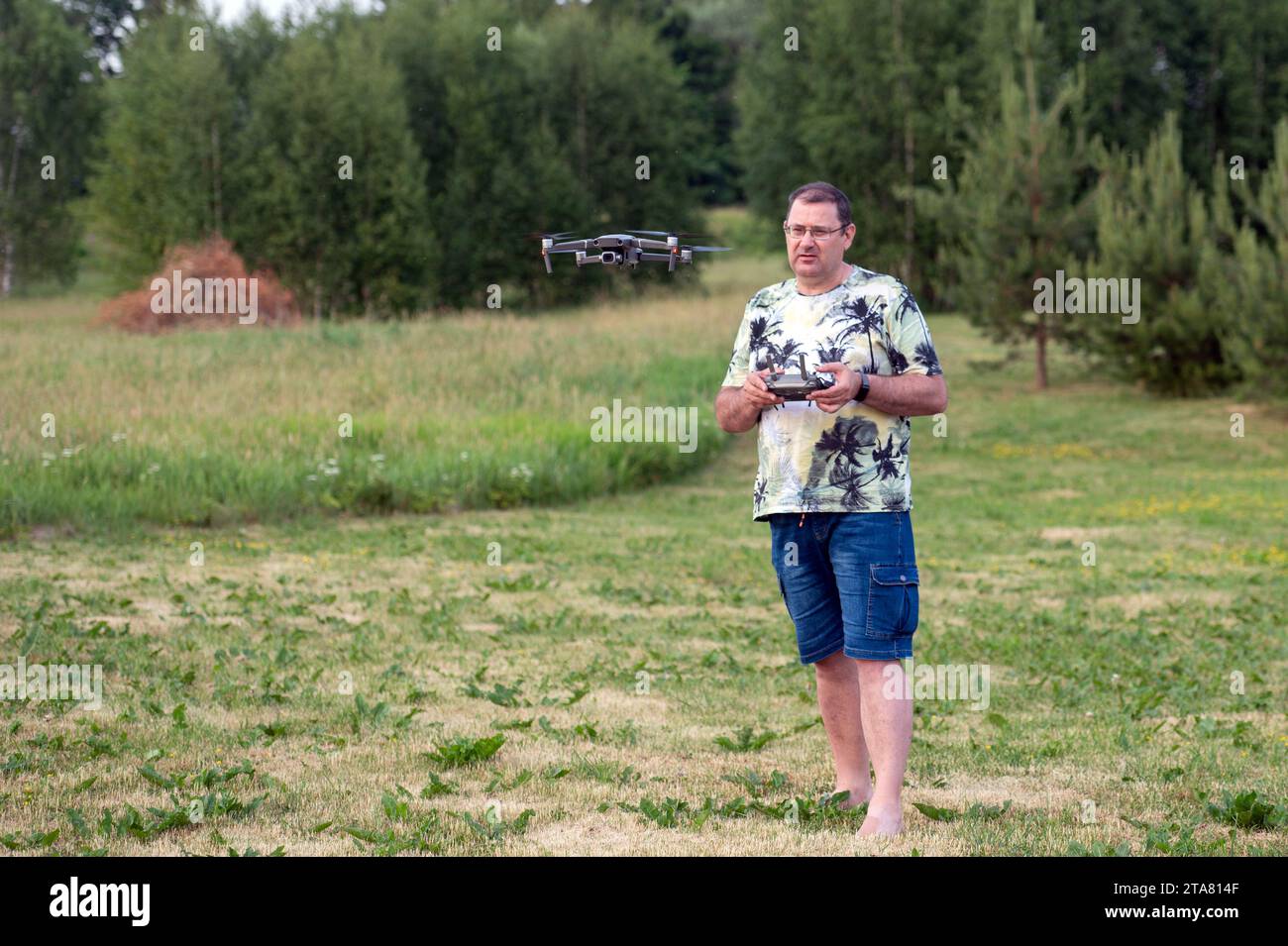 A man operating the drone by remote control on the meadow. Drone pilot ...