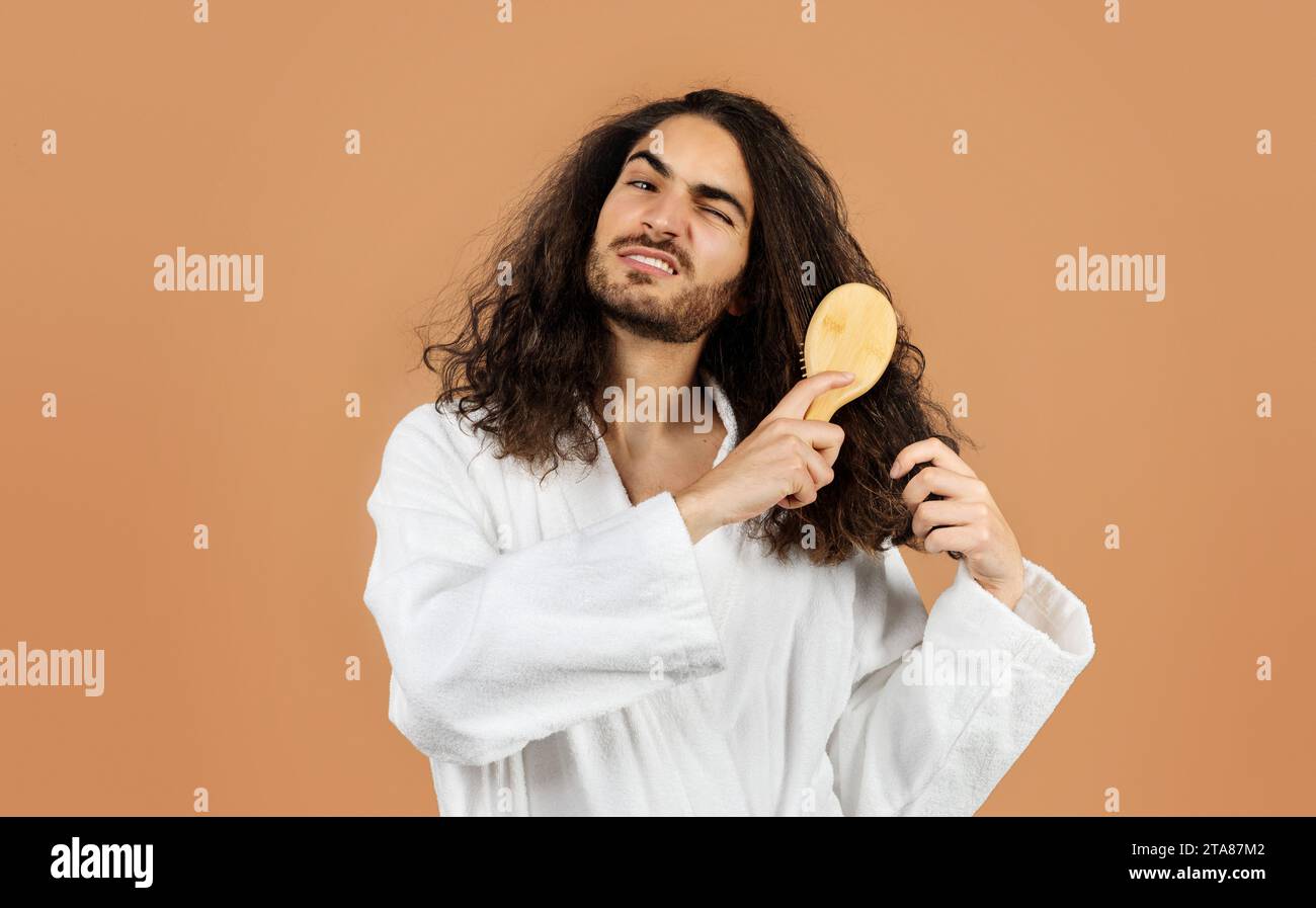 young man combs through curly hair suffering from pain, studio Stock ...