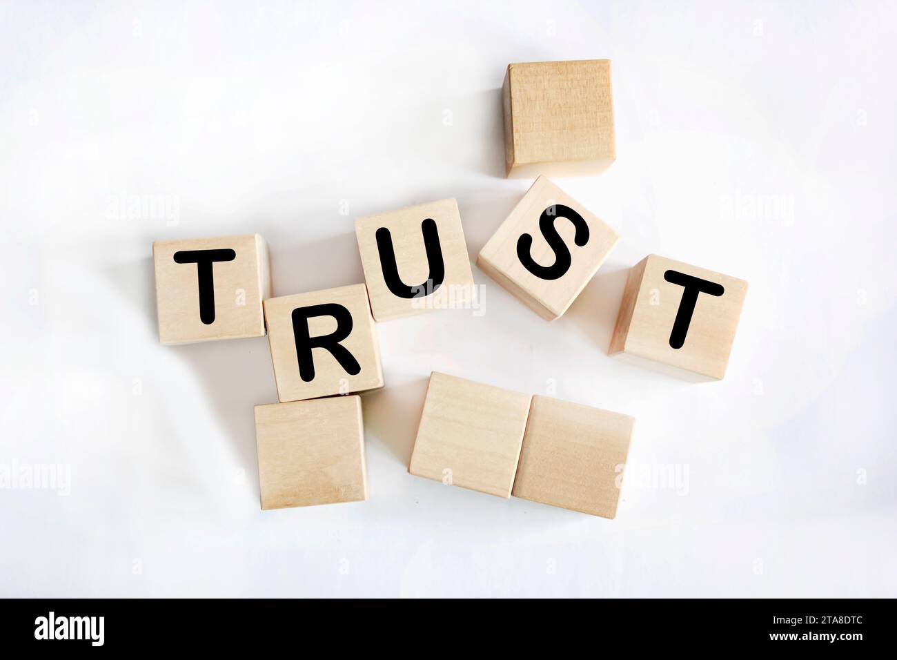 Trust is the word written on wooden blocks. White background. Business ...
