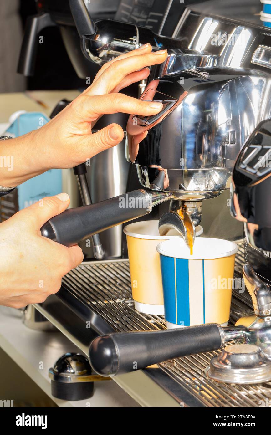 The barista's hands control the coffee machine, the espresso pours ...