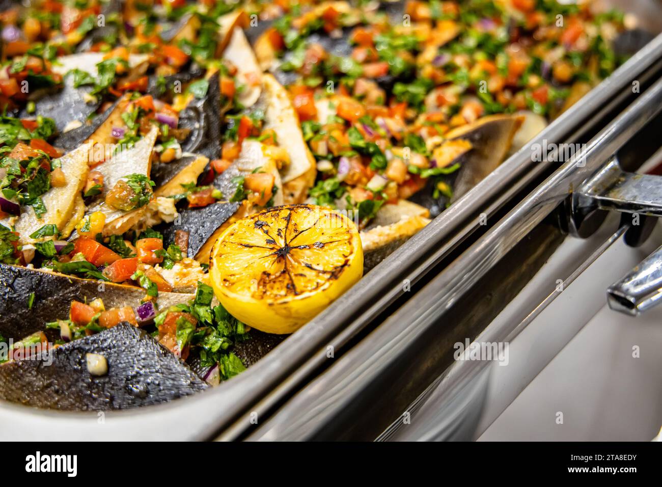 Grilled fish with lemon and vegetables on a metal tray in a restaurant ...