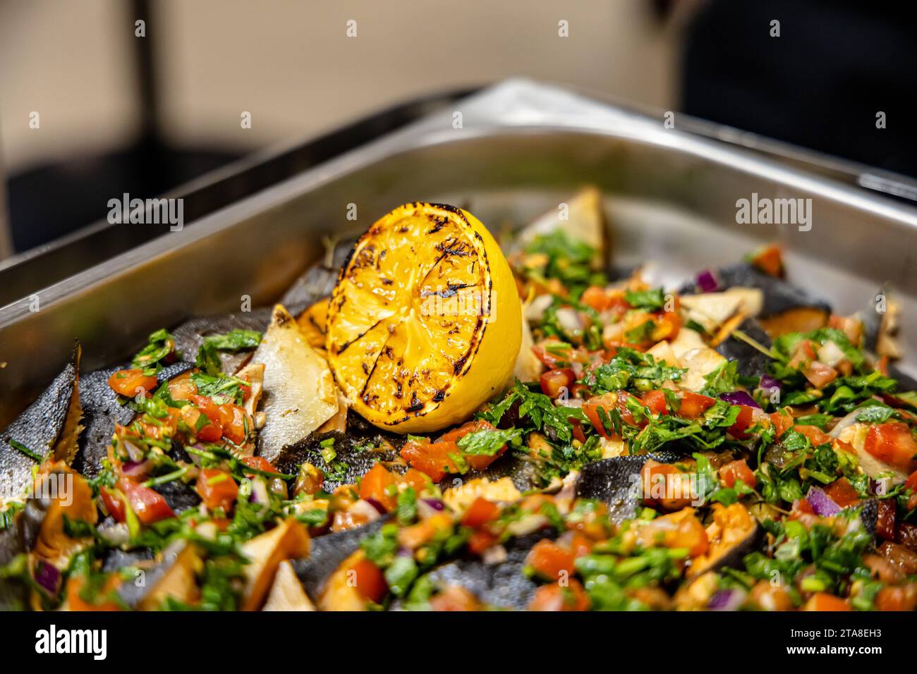 Grilled fish with lemon, parsley and onion on a metal tray. catering ...