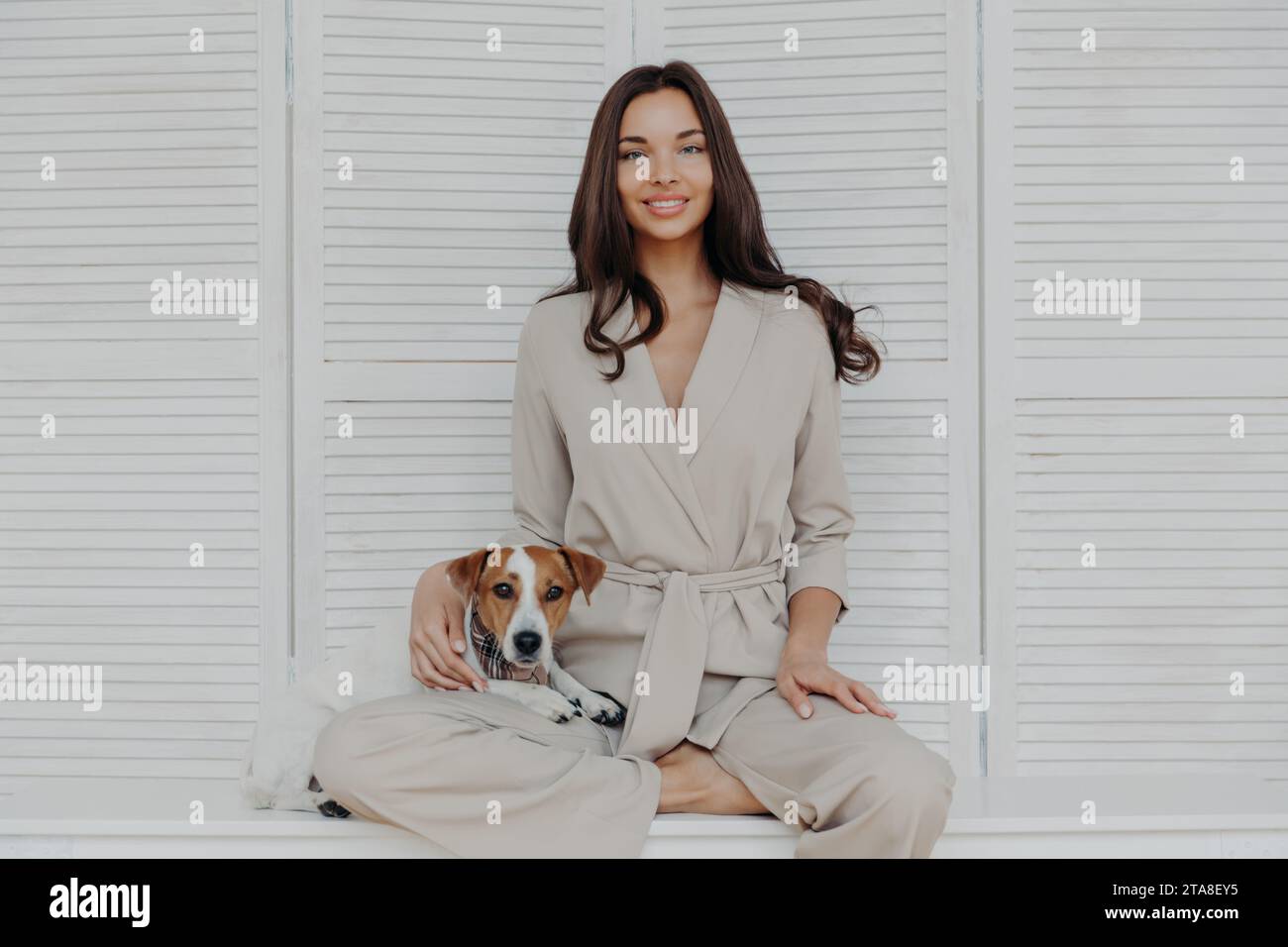 Elegant woman in chic attire with her loyal dog, posing against a white ...
