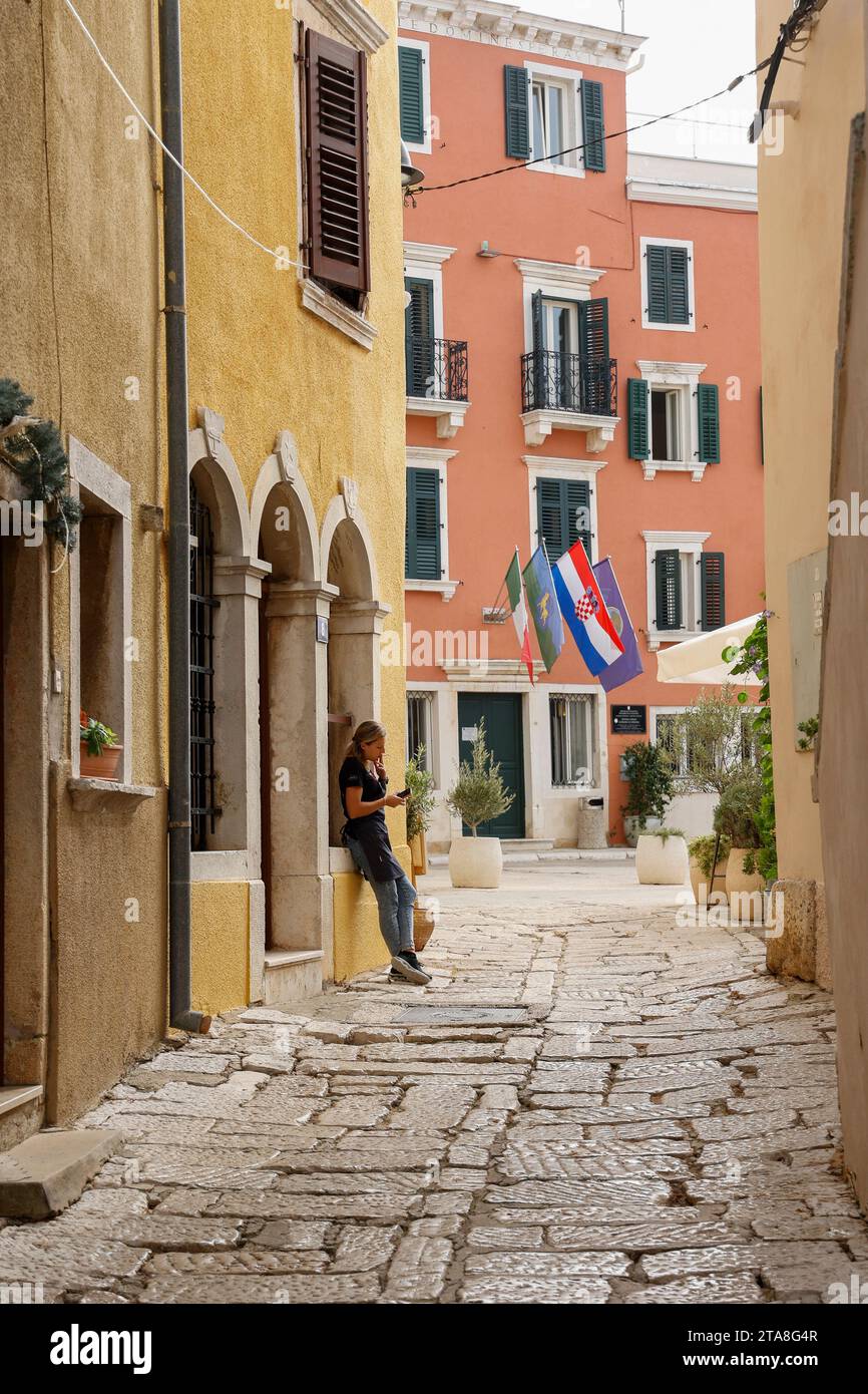 Young woman leaning on wall smoking in cobbled alley near Degrassi ...