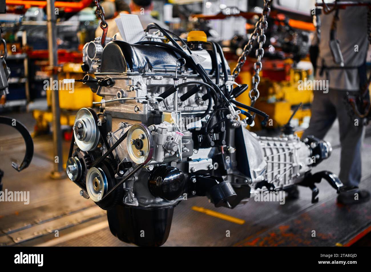 Car motor hangs on chains in assembling plant workshop Stock Photo - Alamy