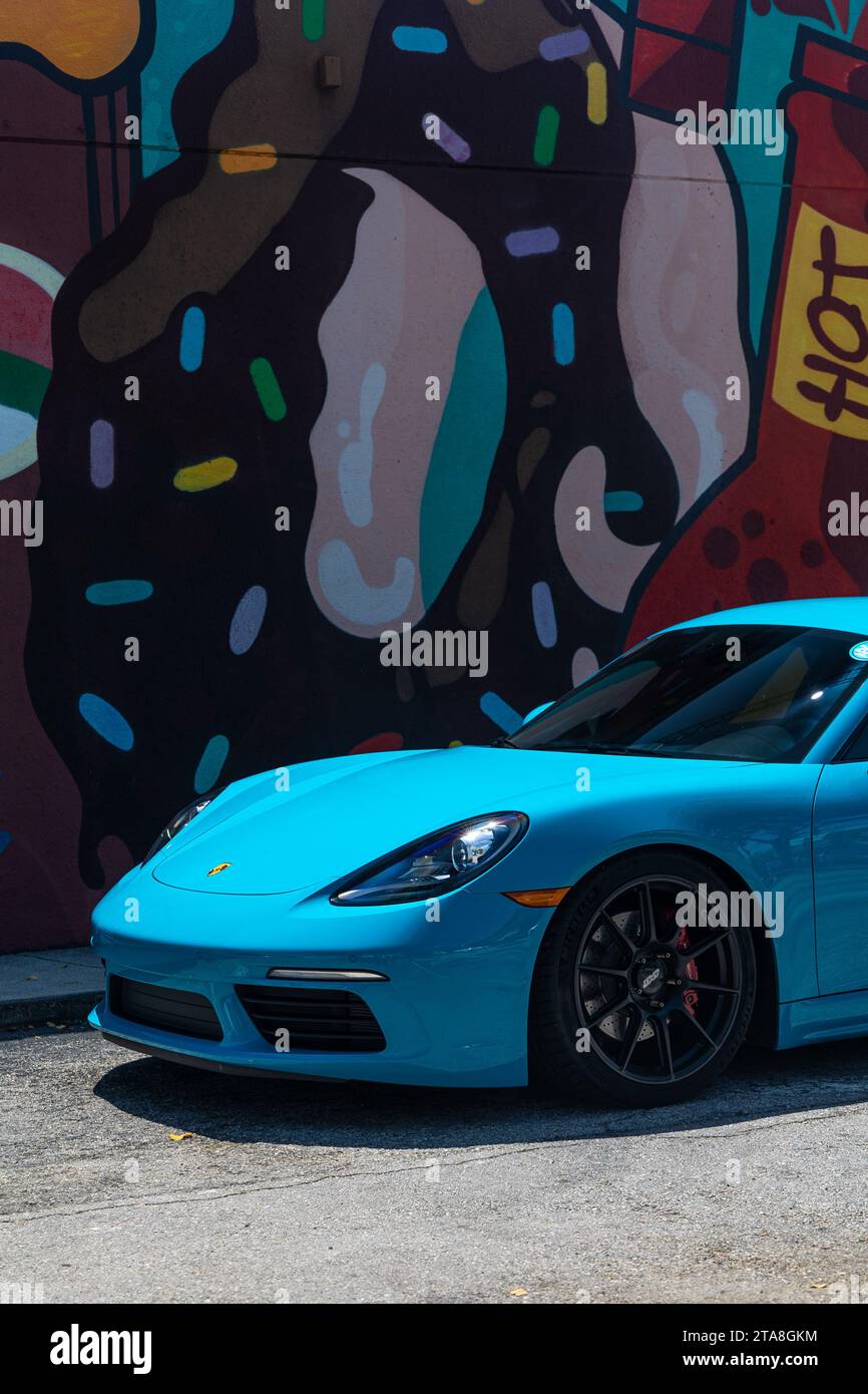 Brightly colored Porsche sports cars parked near a mural in an arts ...