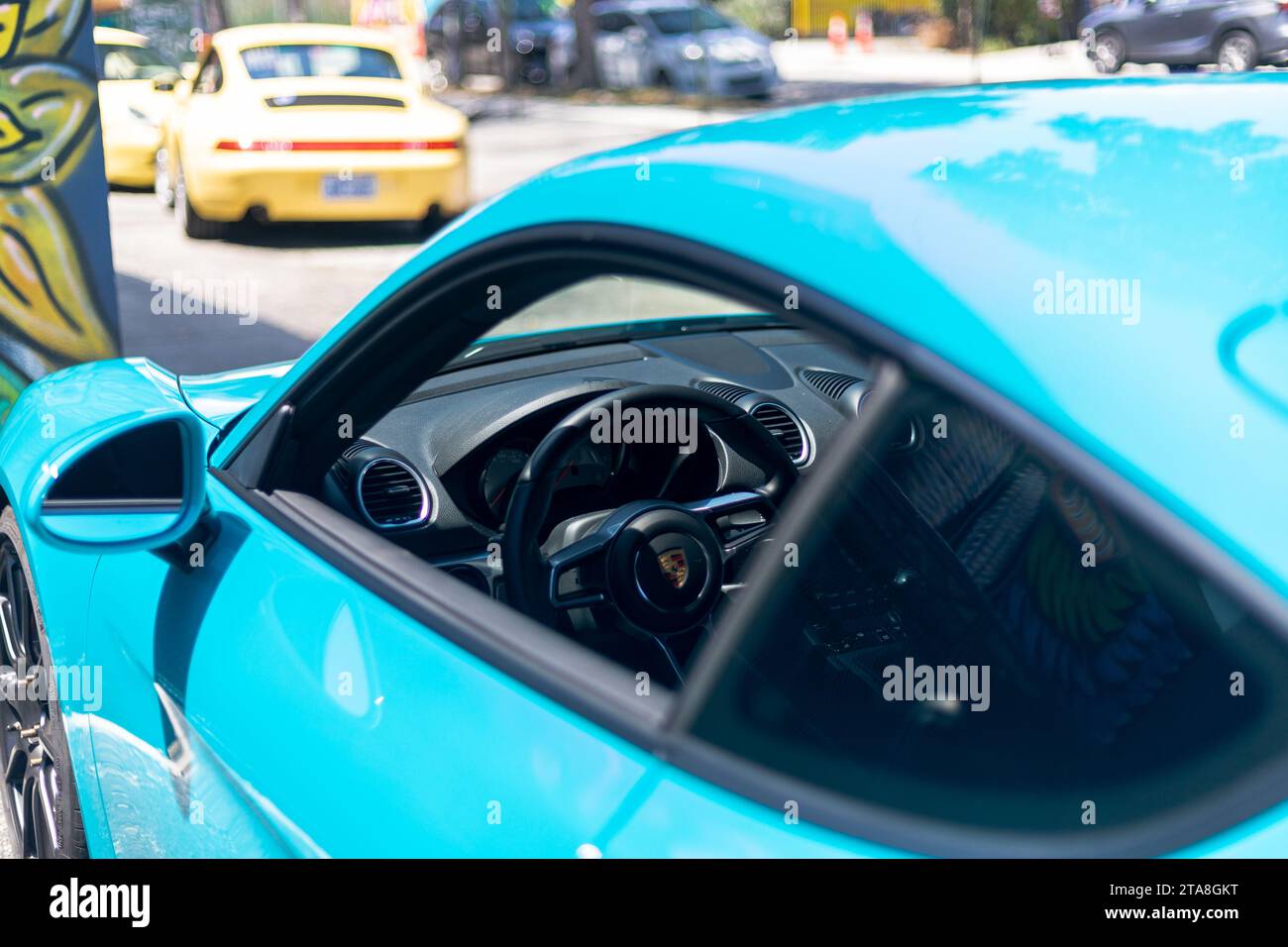 Brightly colored Porsche sports cars parked near a mural in an arts ...