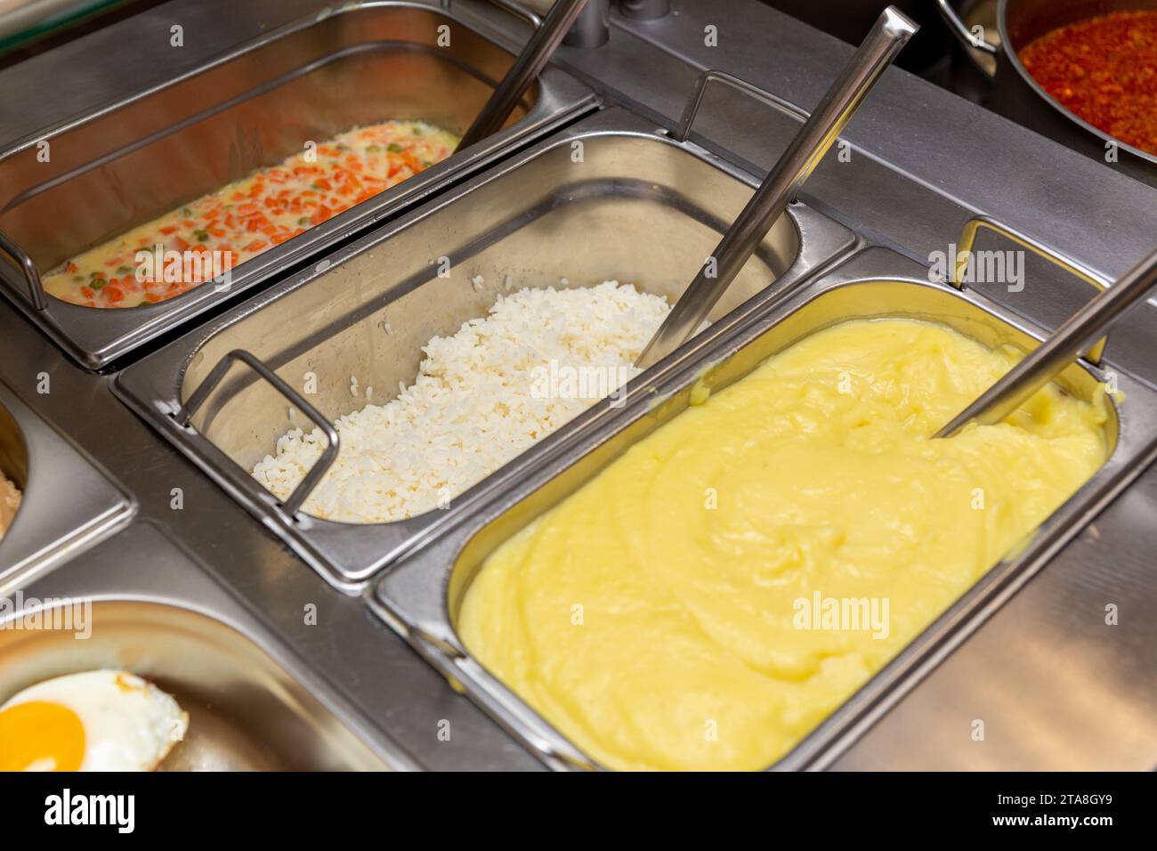 Fast food bistro, food in metal trays, cutlet salads garnish on the ...