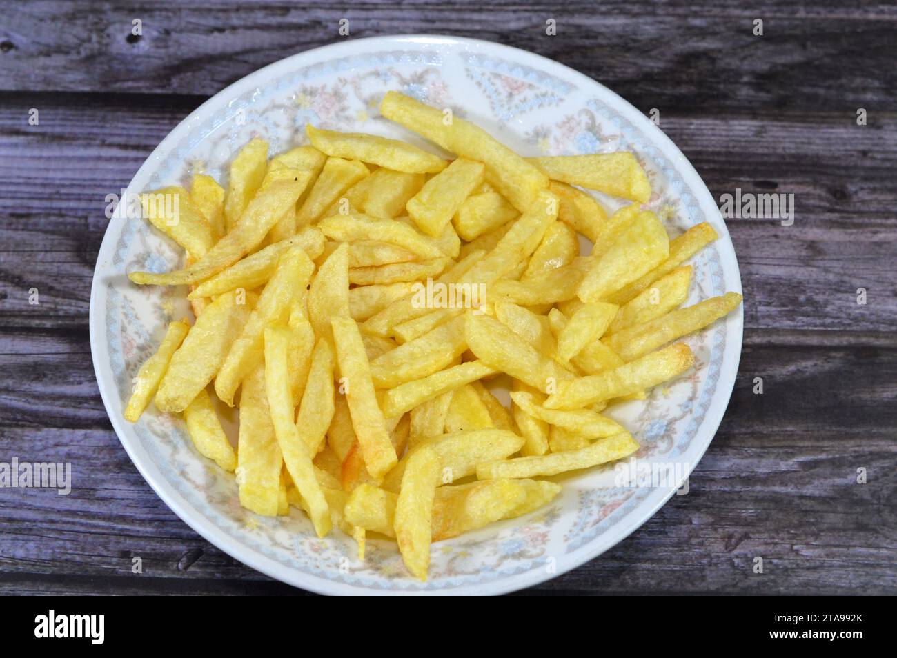 A plate of French fries potatoes fried in boiling hot oil in a deep ...
