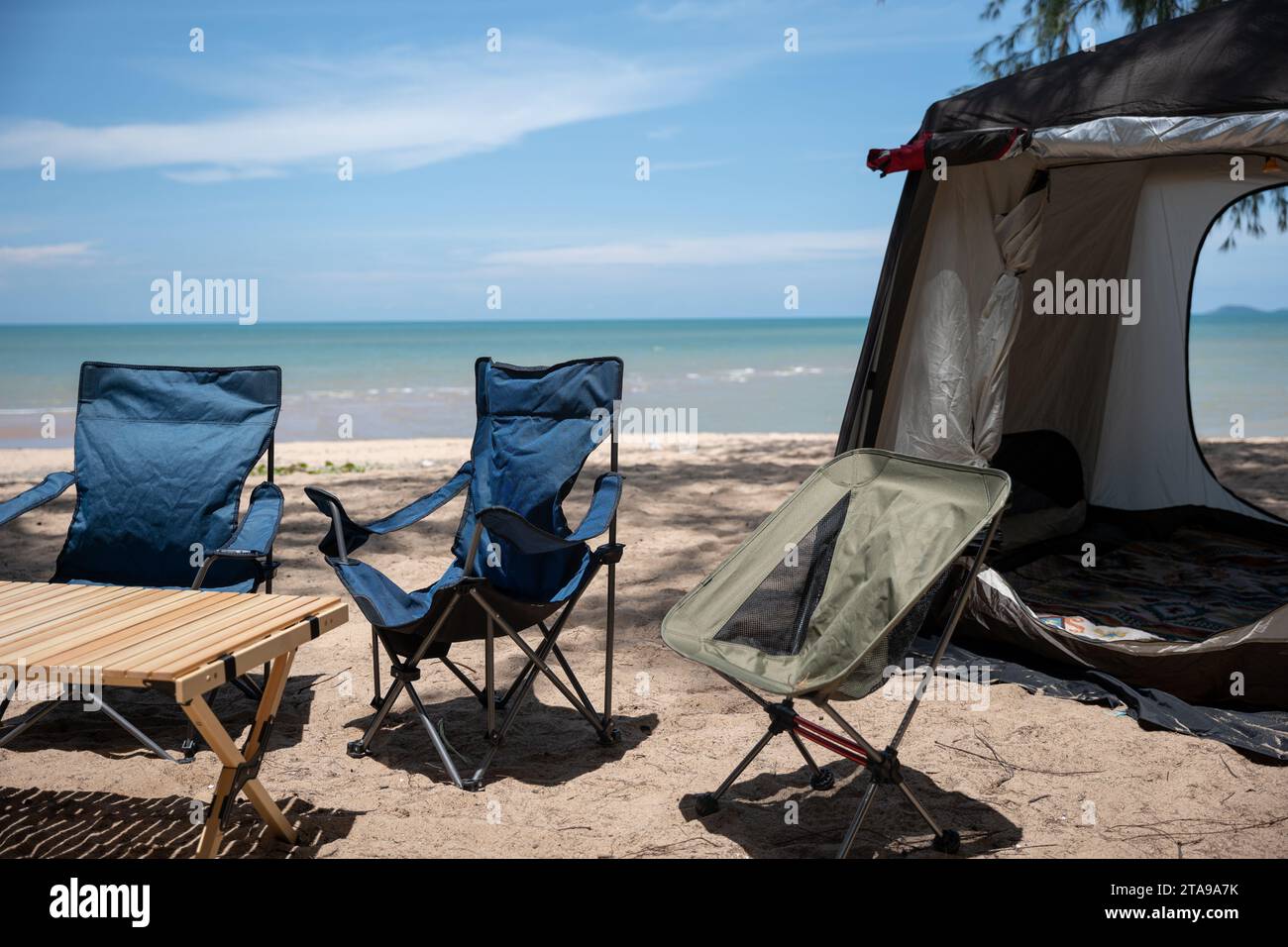 Camping setup on the beach, Chairs, picnic table, and a tent with a ...