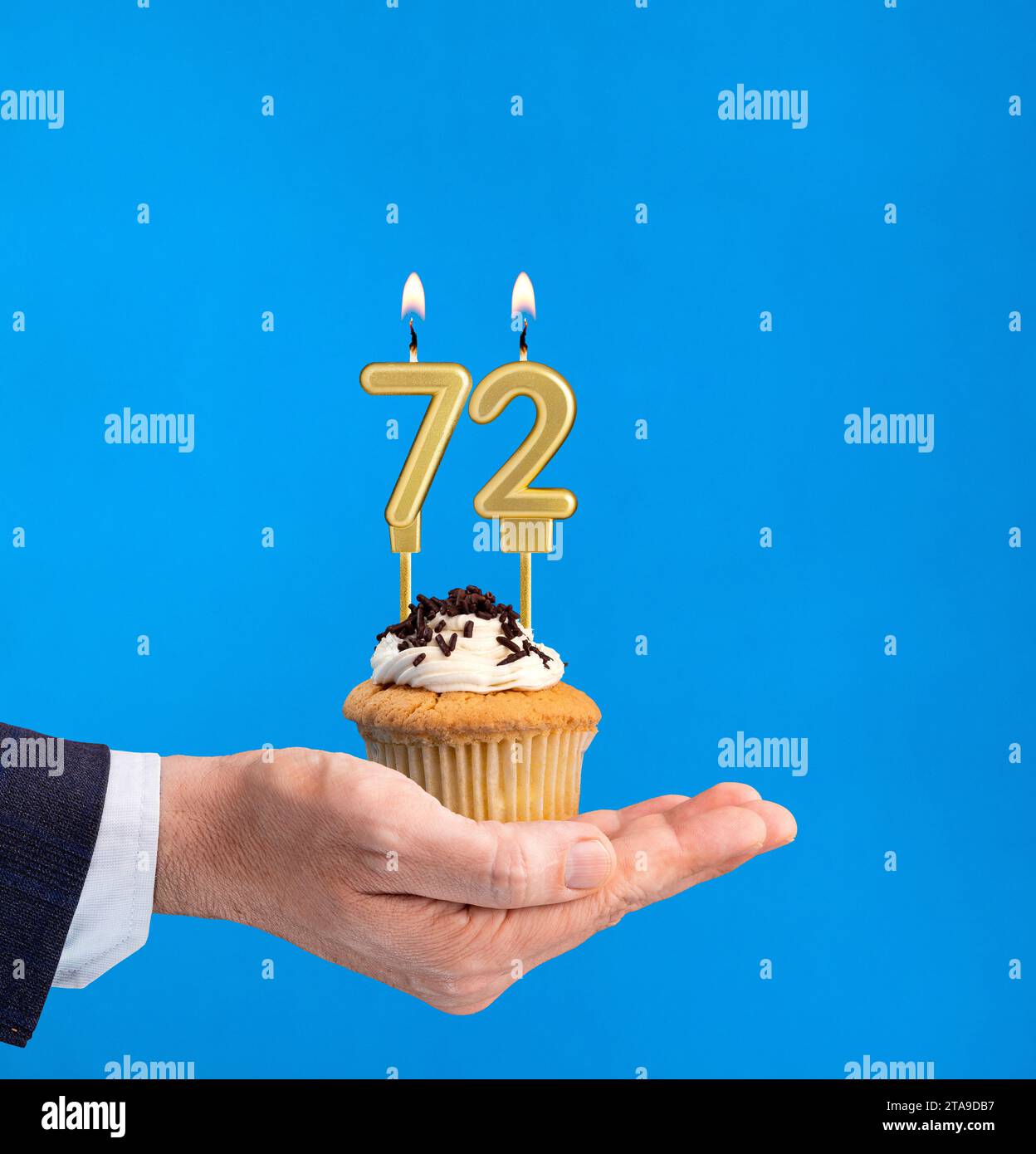 Hand delivering birthday cupcake - Candle number 72 on blue background ...