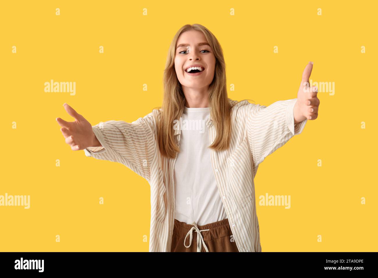 Beautiful woman opening arms for hug on yellow background Stock Photo ...