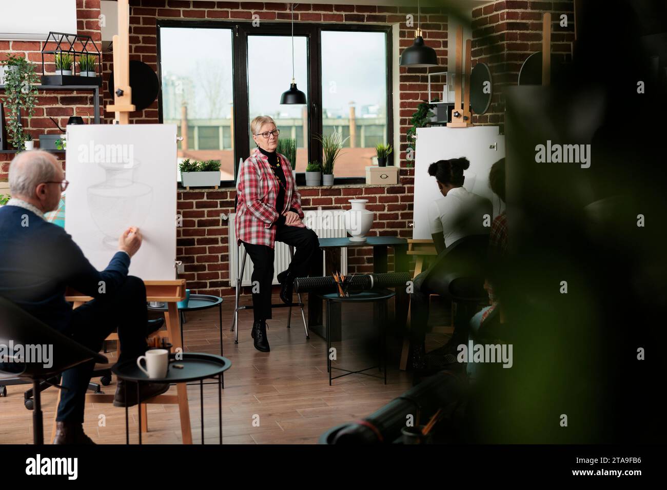 Senior woman professional artist teaching group of students new drawing ...