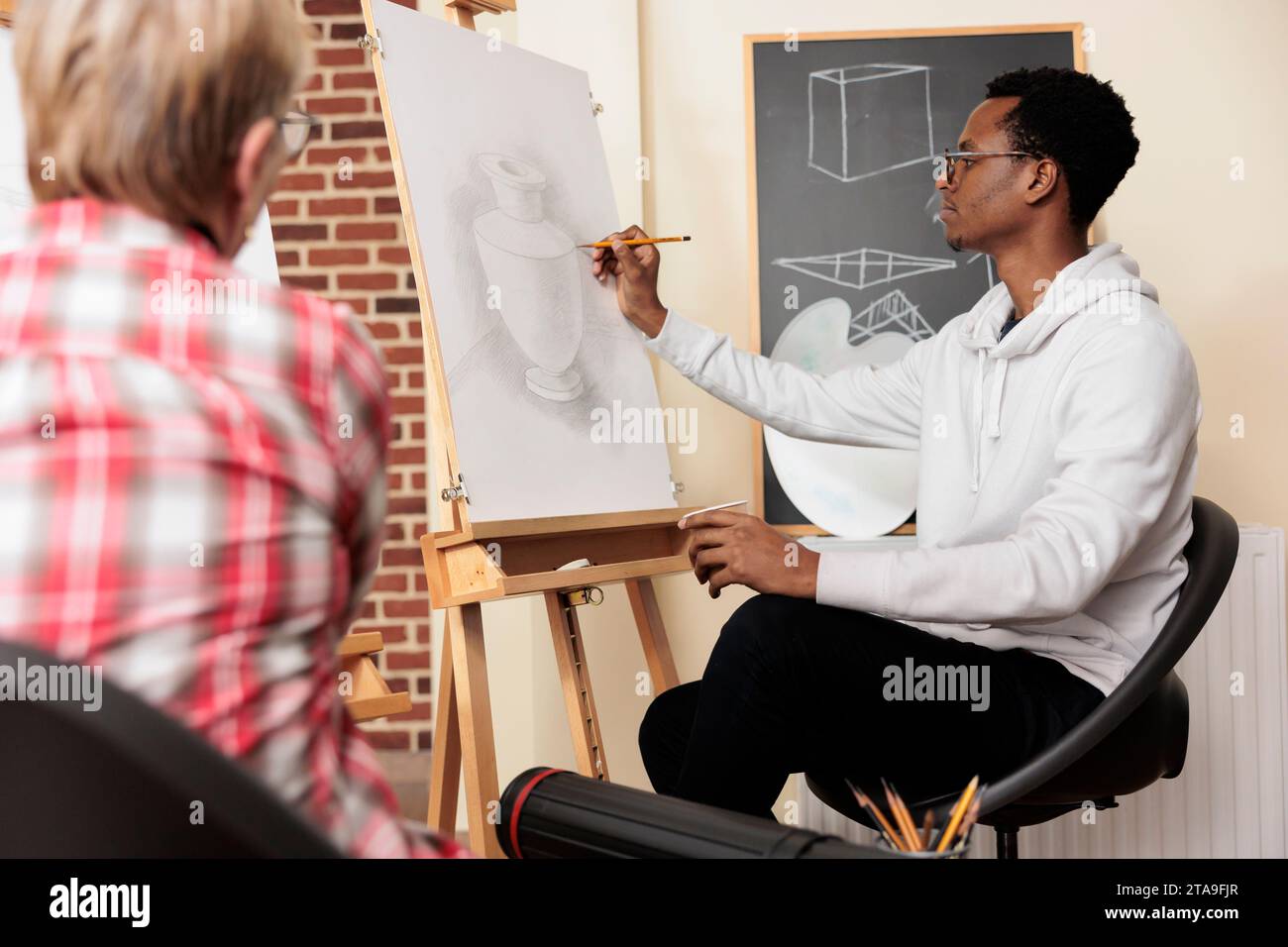 African American millennial guy drawing flower vase on canvas with ...
