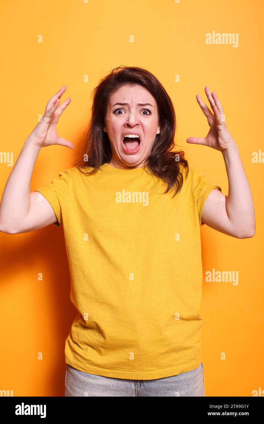 Caucasian woman with open mouth and raised arms, conveying anger and ...