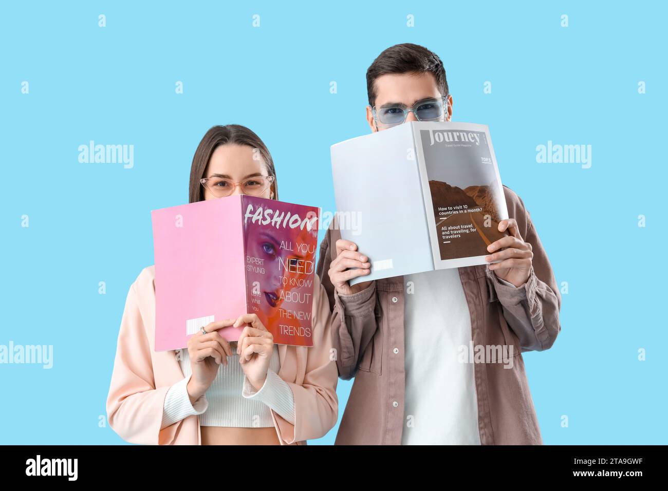 Young couple with magazines on blue background Stock Photo - Alamy