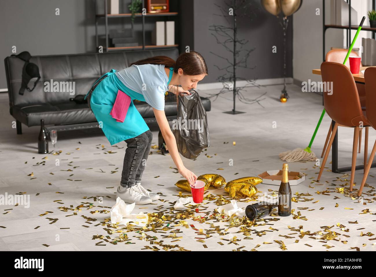 Female janitor taking trash off floor in office after New Year party ...