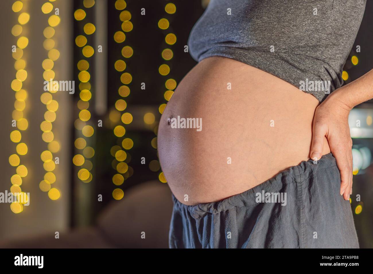 In a warm glow of Christmas lights, a pregnant woman's belly radiates ...