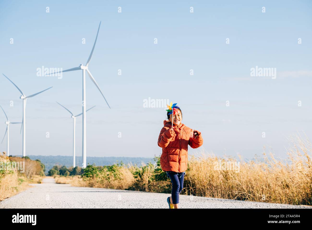 Child's playful exploration by windmills, little girl runs with ...