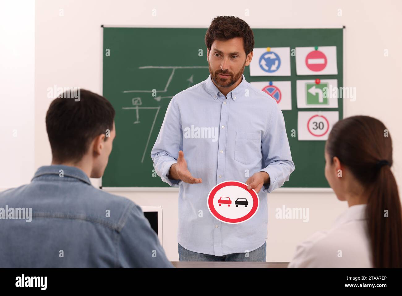 Teacher showing No Overtaking road sign during lesson in driving school ...