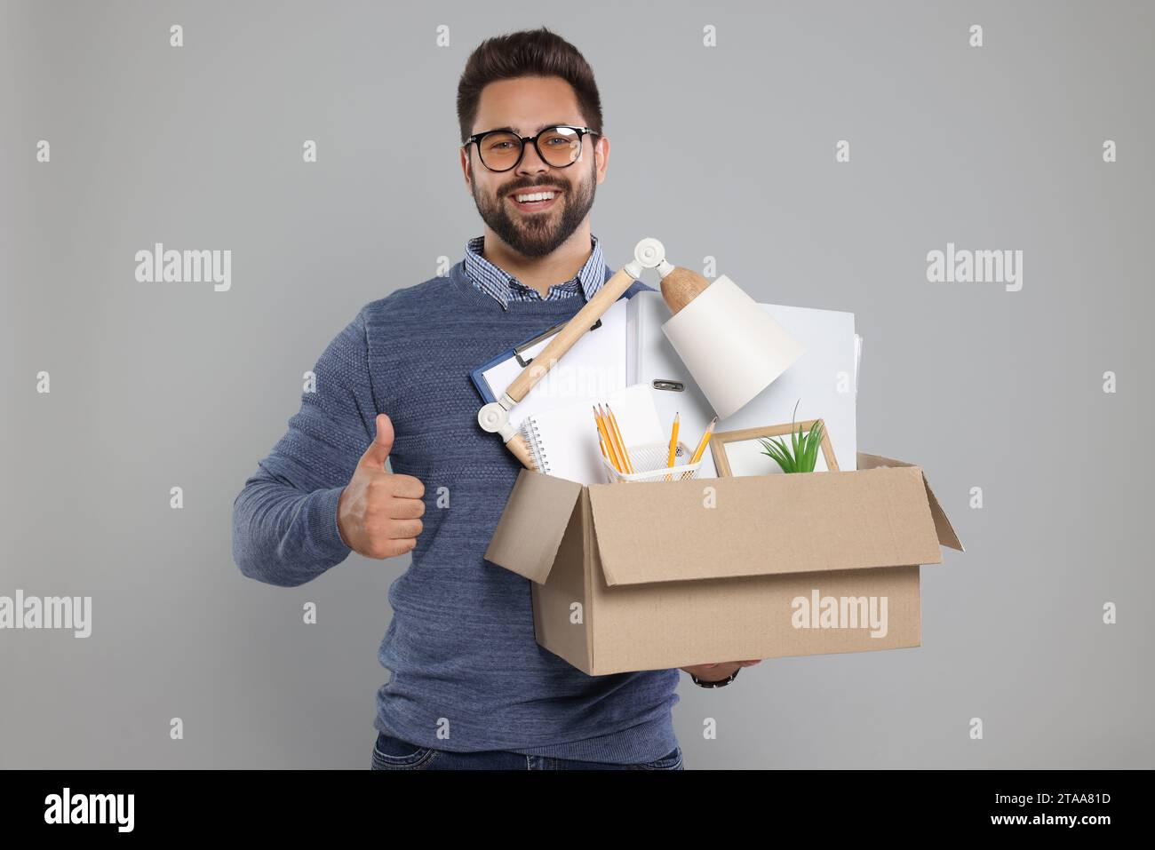 Happy unemployed man with box of personal office belongings showing ...