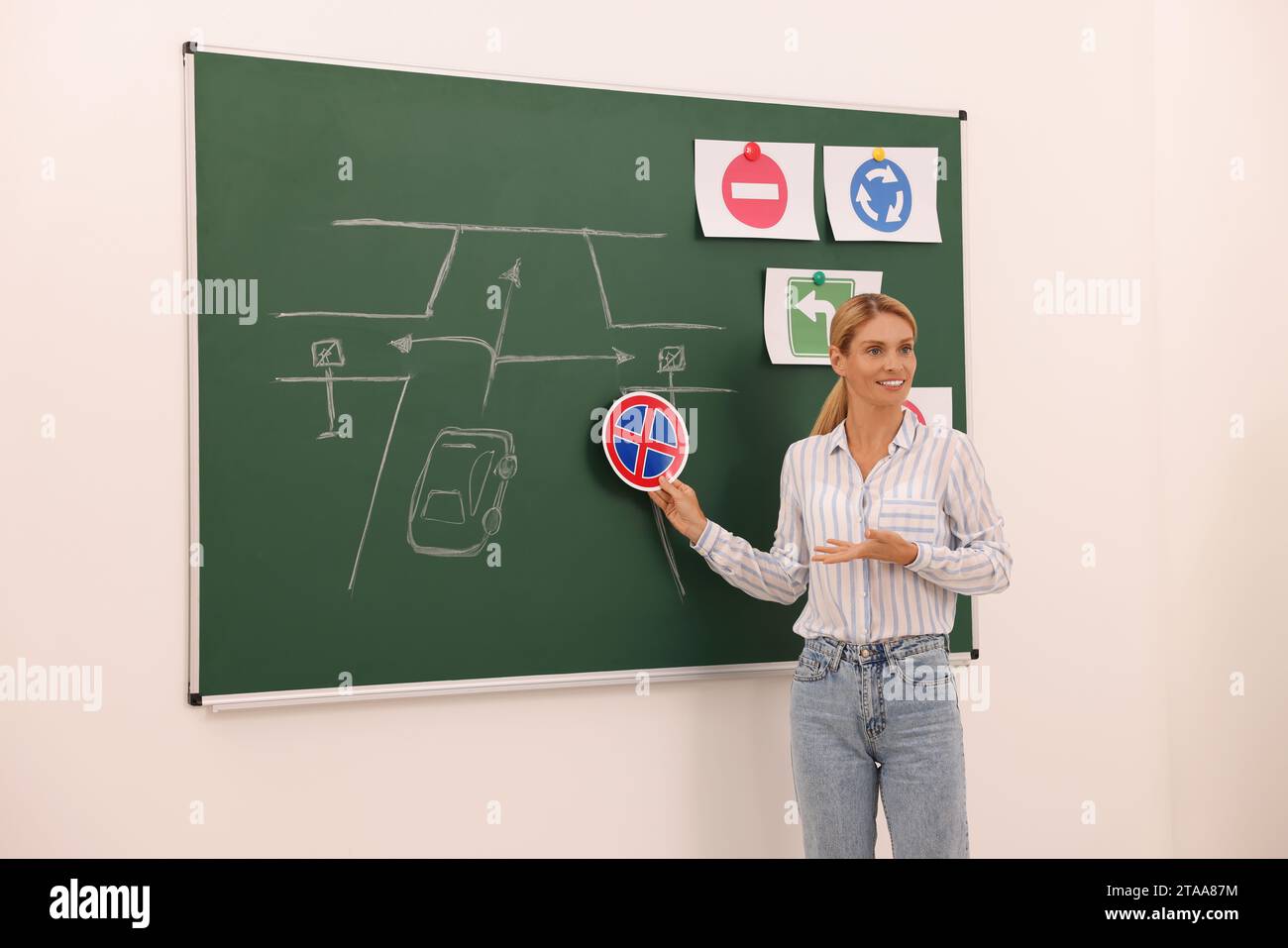 Teacher showing No Stopping road sign near chalkboard during lesson in ...