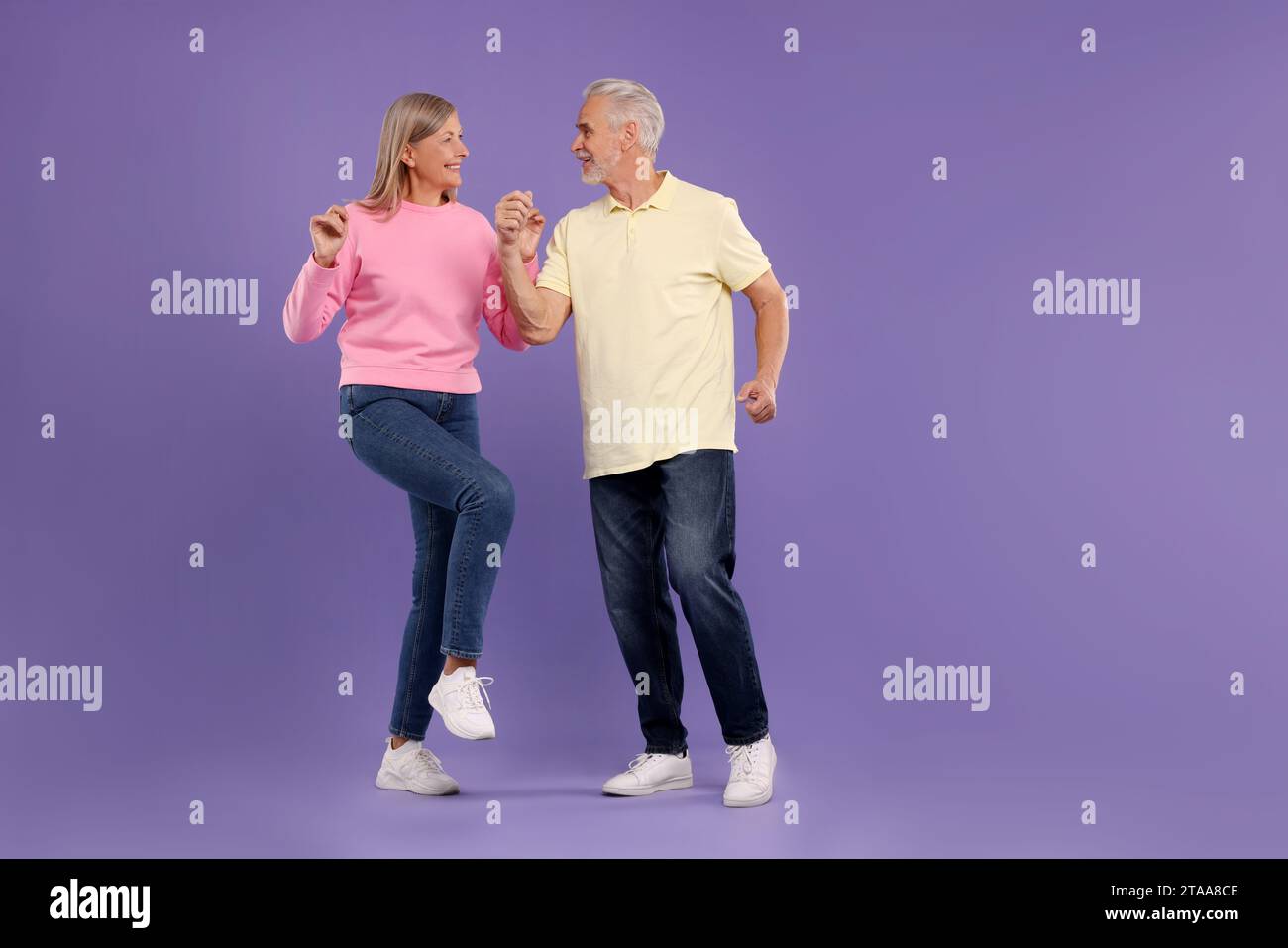 Senior couple dancing together on purple background Stock Photo - Alamy