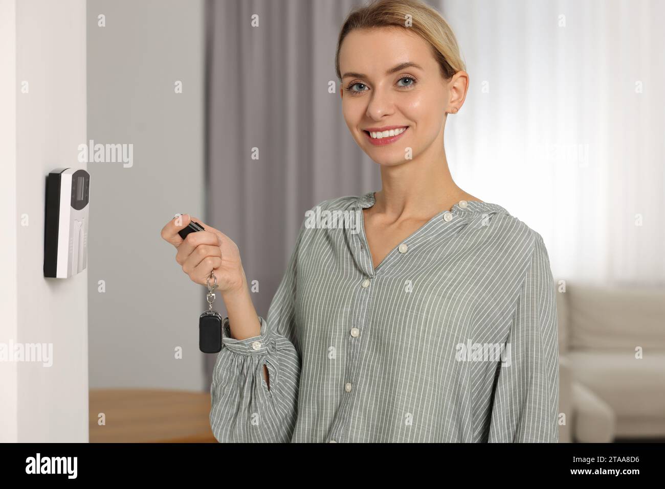 Home security system. Smiling woman using alarm key fob in room Stock ...