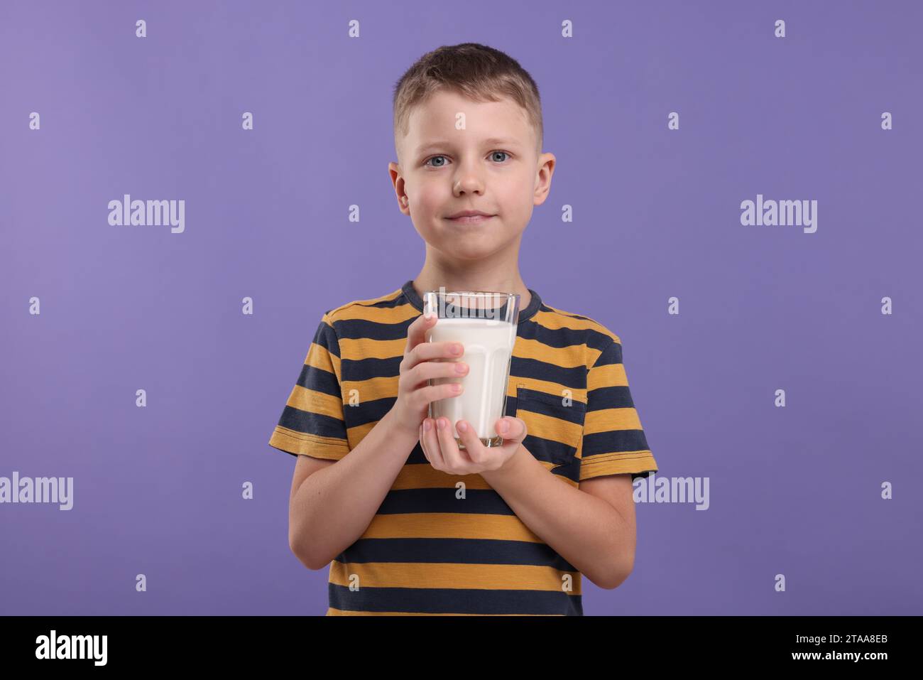 Cute boy with glass of fresh milk on violet background Stock Photo - Alamy