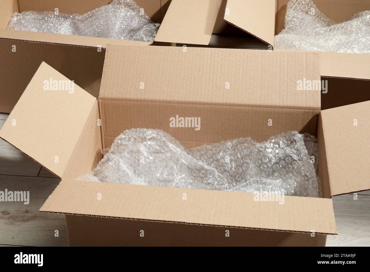 Many open cardboard boxes with bubble wrap on white wooden floor Stock ...
