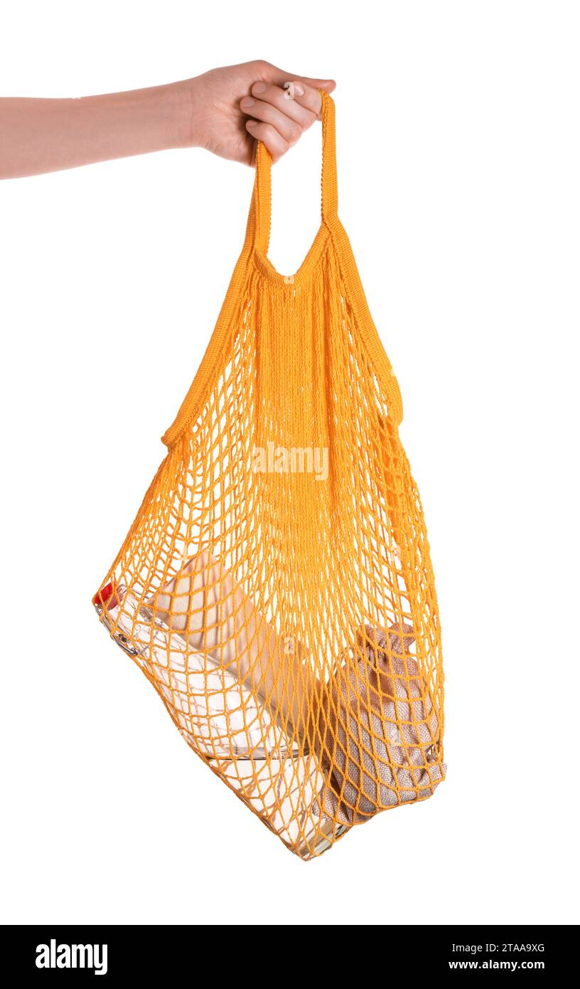 Woman holding net bag with different items on white background, closeup ...