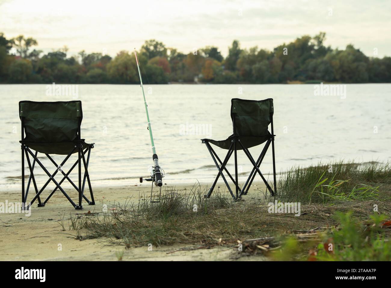 Folding chairs and fishing rod at riverside Stock Photo - Alamy