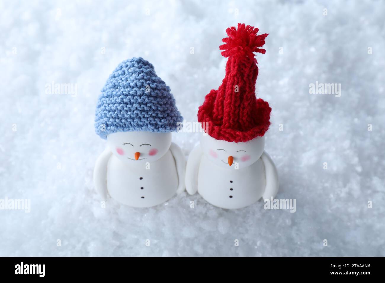 Cute decorative snowmen in color hats on artificial snow Stock Photo ...