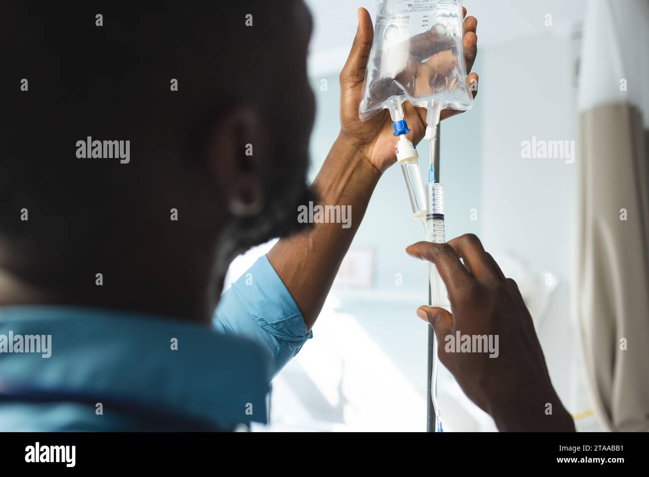 African american male doctor wearing blue shirt applying drip in ...