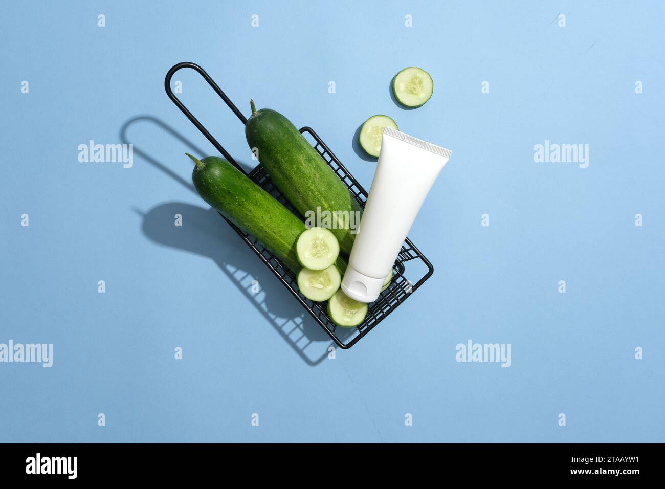 A tube in white color and cucumbers placed inside a black basket ...
